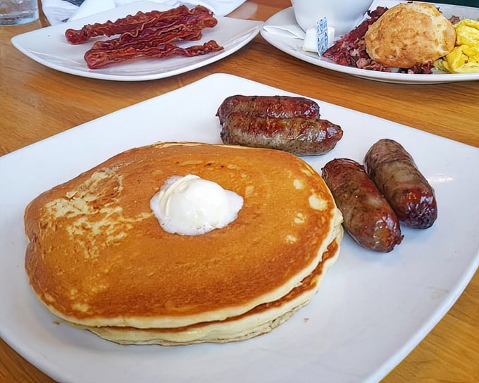 Golden pancakes with a perfect pat of butter melting on top, flanked by sausage links standing at attention like delicious sentries.