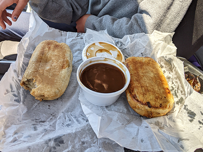 Two golden-brown pasties with a side of gravy—a complete Upper Peninsula meal that miners once carried underground and tourists now travel hundreds of miles to experience.
