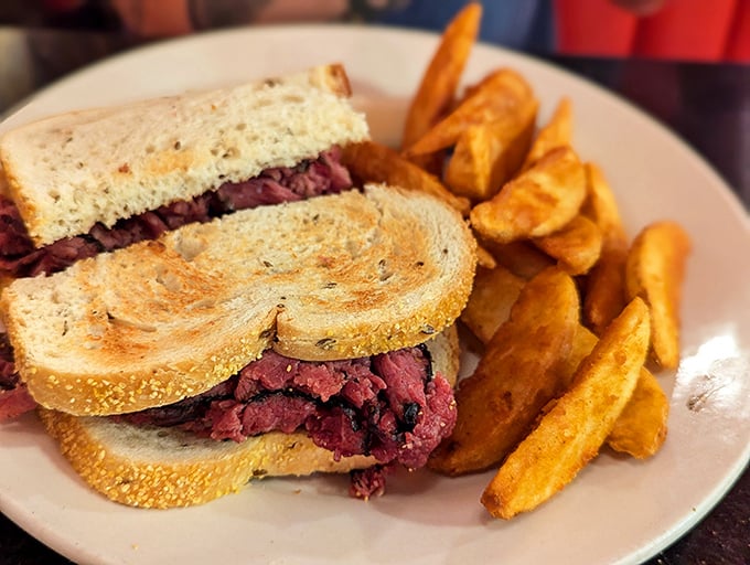 This isn't just a sandwich—it's a monument to pastrami perfection, stacked high between rye bread with golden potato wedges standing guard.