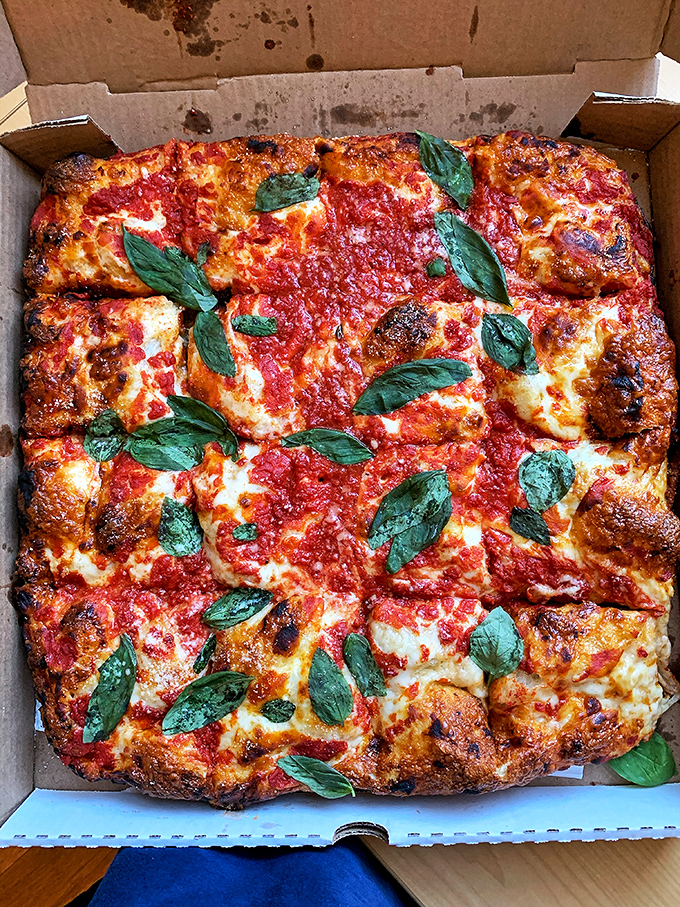 This isn't just pizza—it's a masterpiece of dough, sauce, and basil. The charred edges tell you everything you need to know about the blazing hot ovens.