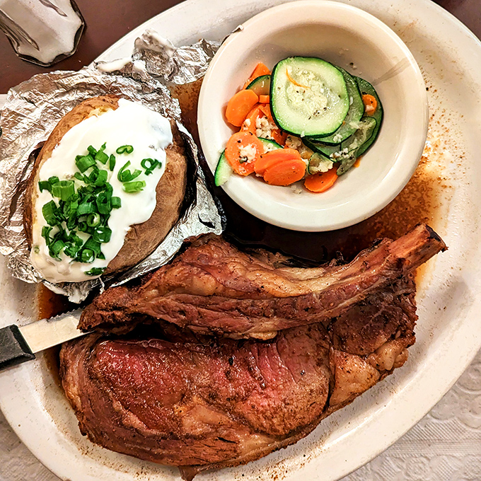 Behold the prime rib in its natural habitat—perfectly pink, accompanied by a loaded baked potato and fresh vegetables. This isn't just dinner; it's edible therapy.