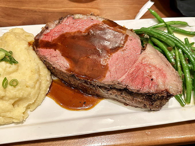 This isn't just prime rib—it's a masterpiece of meat, perfectly pink and accompanied by creamy mashed potatoes and vibrant green beans.