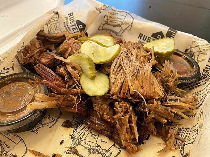 Pulled pork that looks like it's been coaxed apart by angels. Those pickle chips aren't garnish—they're essential acid relief between bites of smoky perfection.