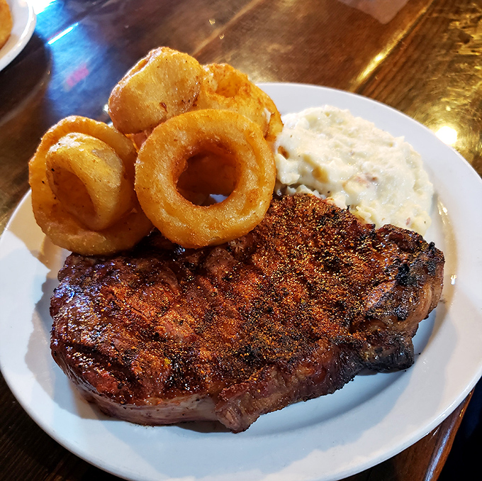 Behold the star of the show – a perfectly charred ribeye with those crispy onion rings and creamy mashed potatoes that'll haunt your dreams.