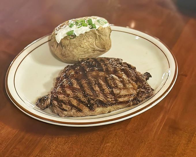 Simplicity at its most sublime—a perfectly grilled ribeye with classic baked potato. No foam, no tweezers, no nonsense—just honest-to-goodness steak perfection.