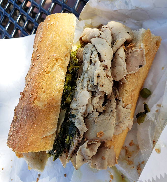 Behold the roast pork sandwich in its natural habitat—tender meat and vibrant greens nestled in a roll that's achieved bread perfection.