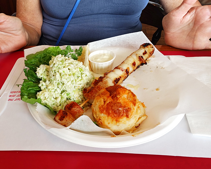 Seafood perfection on paper plates: a golden crab cake, fresh coleslaw, and a perfectly grilled skewer that proves luxury isn't about the dinnerware.