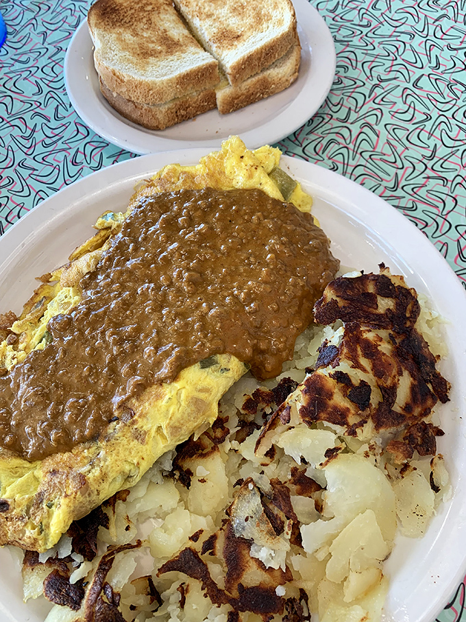 Behold the legendary Southern Omelet in its gravy-cascading glory. Those perfectly crisped hash browns aren't just a side—they're an essential supporting character.