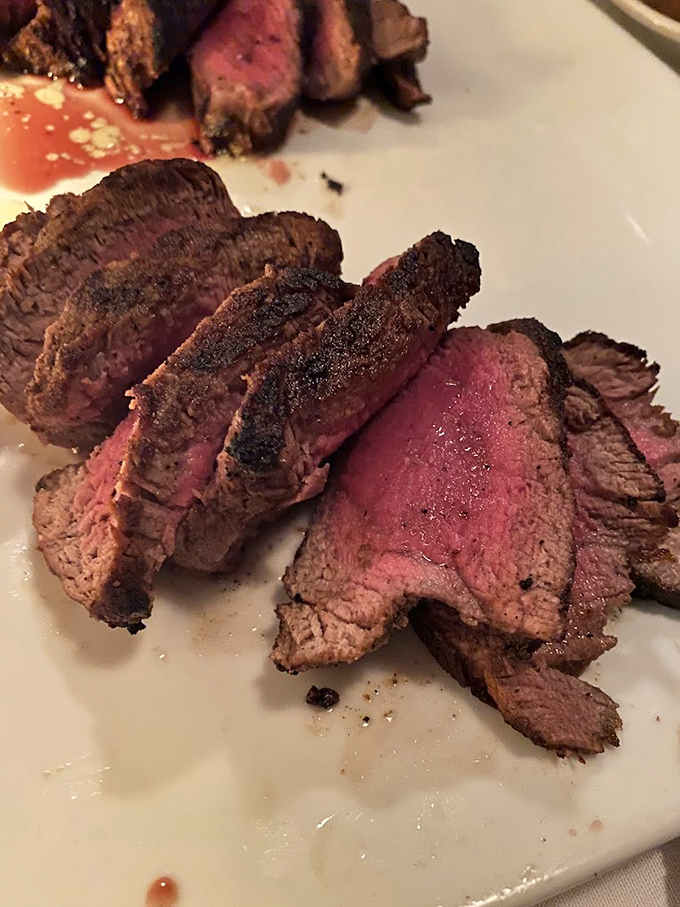 Perfectly sliced medium-rare steak revealing that gorgeous pink center—the kind that makes vegetarians question their life choices. 