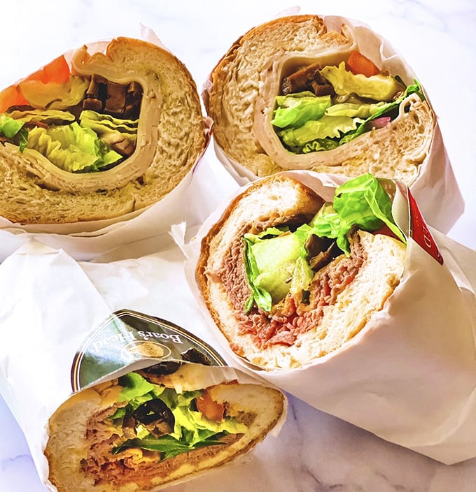 A quartet of Mickey's subs in their natural habitat – wrapped in paper, bursting with fillings, and moments away from causing involuntary food moans.