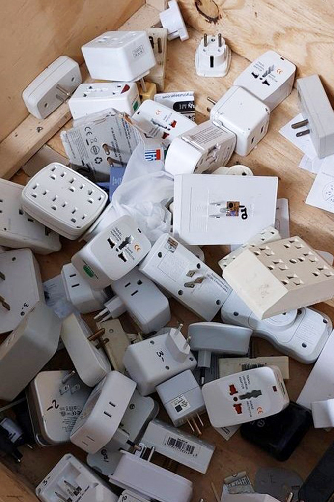 The electrical adapter graveyard: where international travel souvenirs and forgotten tech come to find new purpose in someone else's journey.
