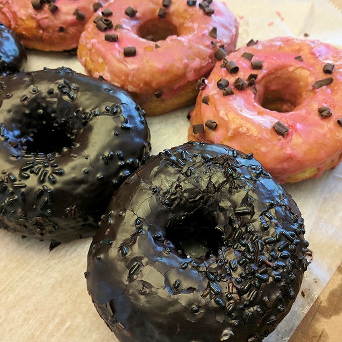 Chocolate glazed beauties with sprinkles alongside pink-frosted delights. These aren't just donuts—they're edible art with attitude.