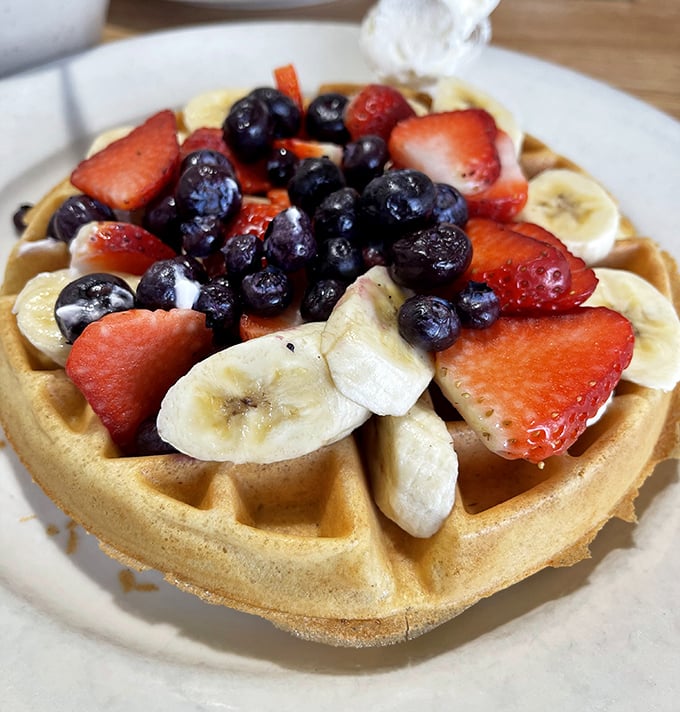 This isn't just a waffle—it's a golden canvas for nature's candy. Blueberries, strawberries, and bananas transform breakfast into an edible work of art.