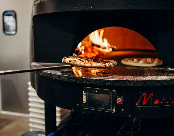 Where pizza dreams are born—watching dough transform in the fiery belly of a wood-fired oven is dinner theater at its finest.