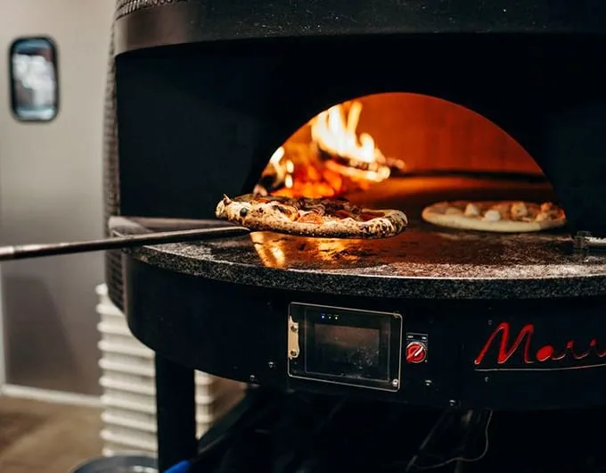 Where pizza dreams are born—watching dough transform in the fiery belly of a wood-fired oven is dinner theater at its finest.