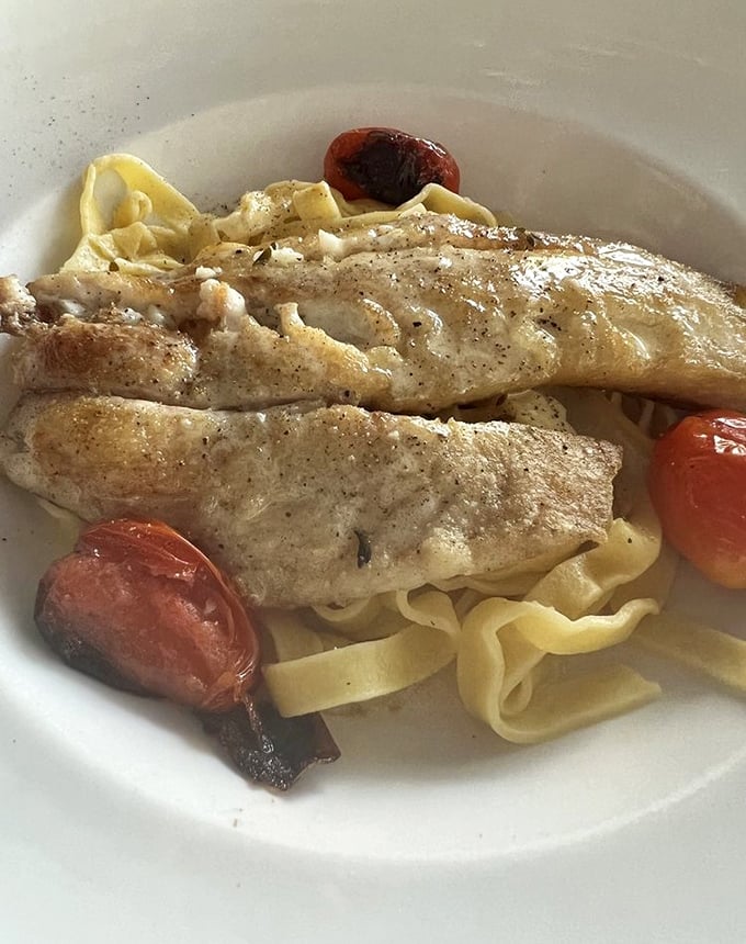 The legendary yellowtail snapper that's worth the drive. Perfectly flaky fish nestled on pasta with roasted tomatoes – simplicity that speaks volumes.