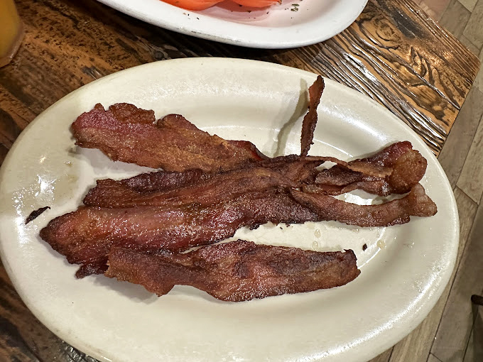 Behold the legendary Millionaire's Bacon – thick-cut, caramelized, and glistening with sweet-spicy goodness. This isn't breakfast meat; it's breakfast theater on a plate..