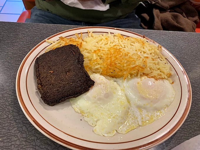 Simplicity at its finest – perfectly cooked eggs, crispy hash browns, and what appears to be livermush, a Carolina breakfast tradition worth discovering.