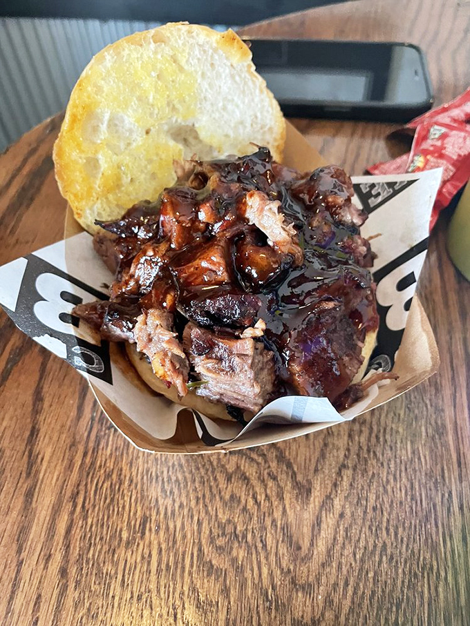 Behold the brisket sandwich in its natural habitat—glistening with sauce, bark intact, ready to transport you to a higher plane of existence.