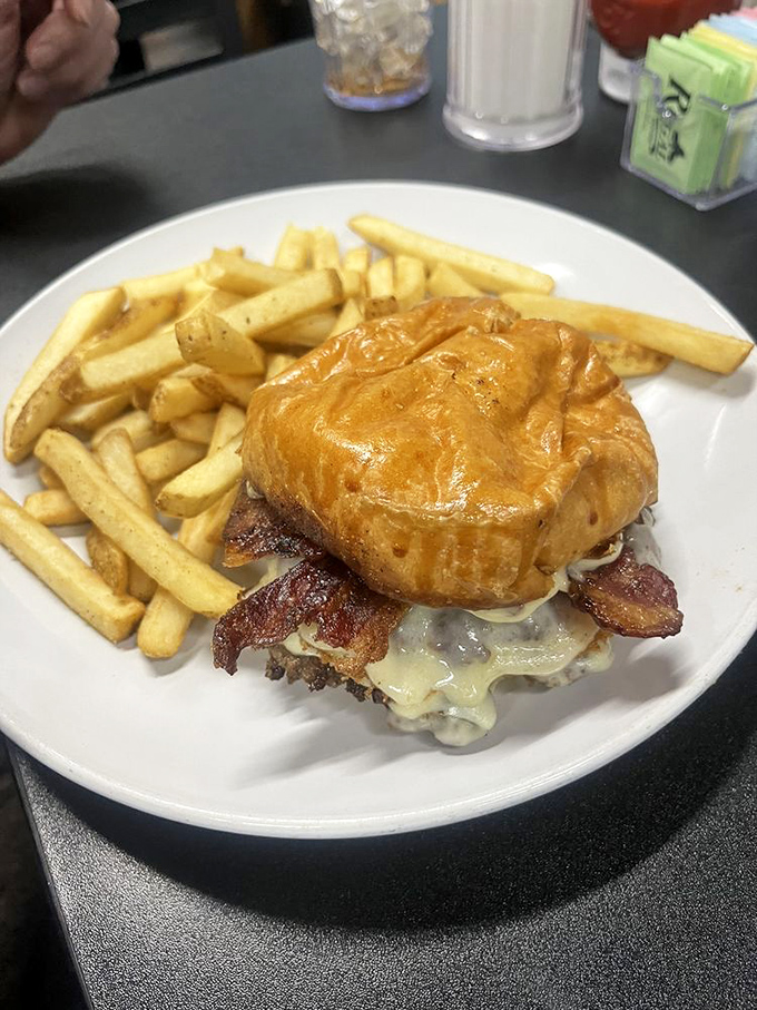 This isn't just a burger; it's a masterpiece of melty cheese cascading over bacon and beef, with fries standing by for their supporting role.