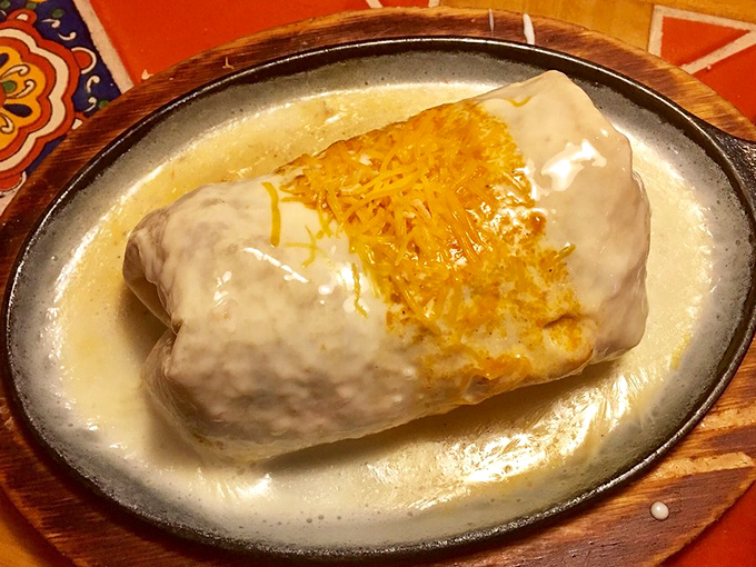Behold the burrito in its natural habitat—swimming in a pool of queso. This isn't just dinner; it's therapy wrapped in a tortilla. 