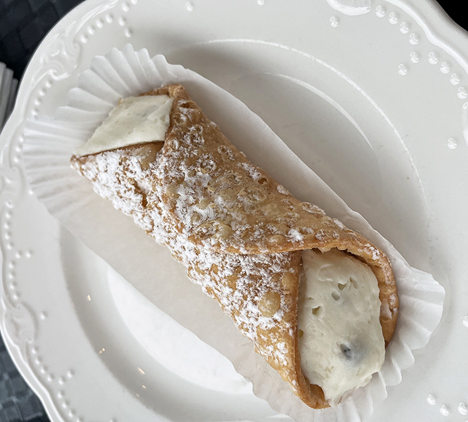 The star of the show: a perfectly crisp cannoli shell filled with sweet ricotta cream and dusted with powdered sugar—proof that the simplest pleasures are often the most profound.