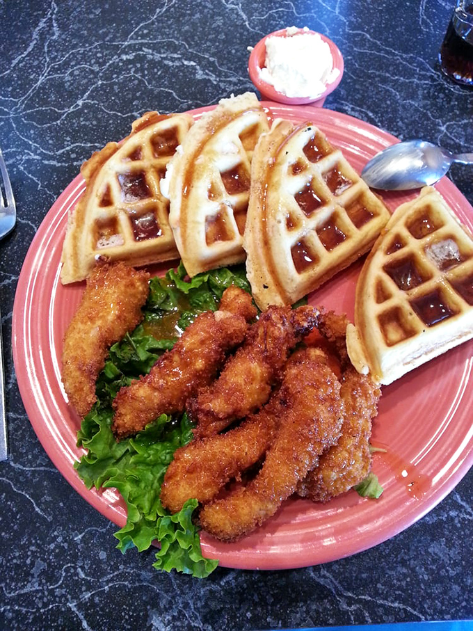 Golden-crisp chicken and waffles served on a coral plate—a sweet-savory romance that makes you wonder why we ever separated breakfast from dinner.