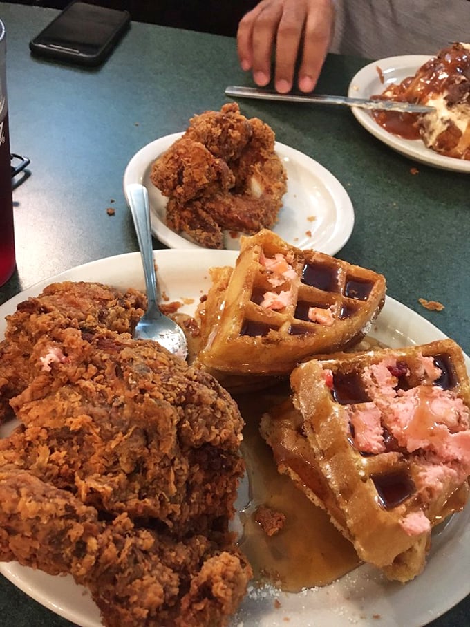 Behold the star attraction: golden-brown fried chicken perched atop Belgian waffles with strawberry butter. This isn't breakfast—it's an edible hug.