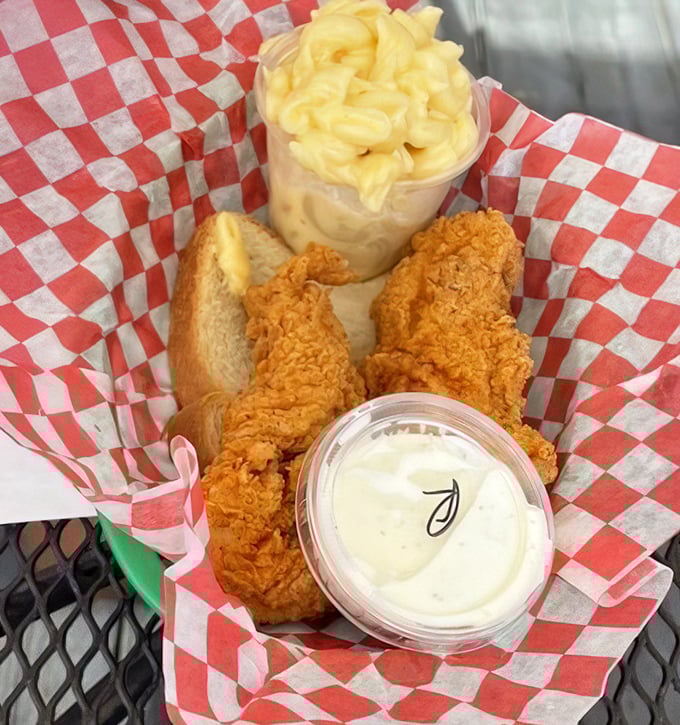 Golden-brown chicken tenders nestled in checkered paper with mac and cheese that's unapologetically creamy—this is what comfort food dreams are made of.