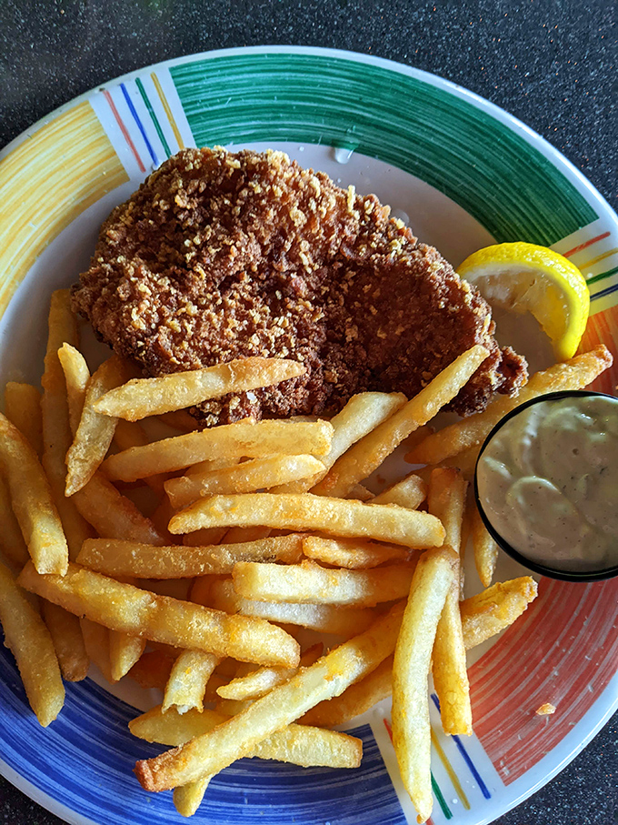 Golden-battered fish perched atop a mountain of crispy fries – this isn't just fish and chips, it's edible sunshine on a colorful plate.