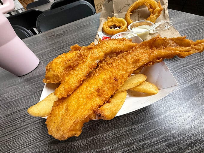 Golden-battered fish fillets perched atop thick-cut chips—this isn't just food, it's edible architecture designed by someone who understands comfort.