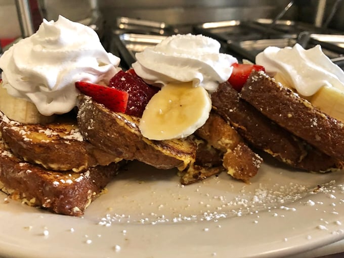 This isn't just French toast – it's a masterpiece of custard-soaked perfection topped with fresh fruit and whipped cream that would make Julia Child weep with joy.