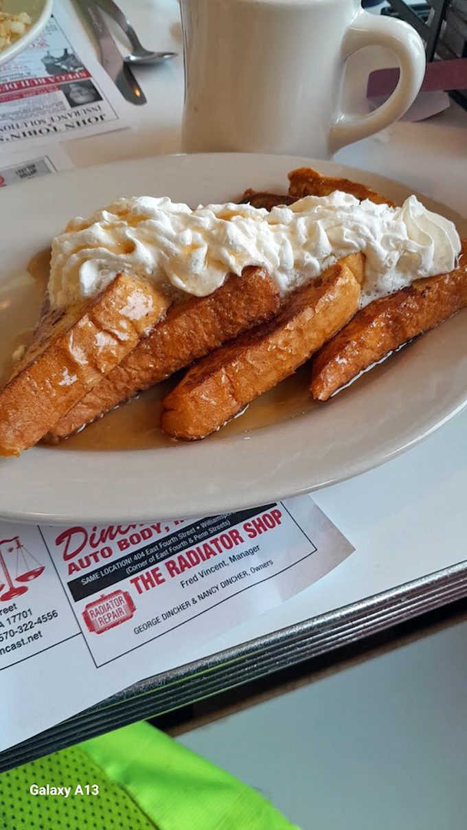 French toast nirvana! Golden-brown slices hiding a custardy interior, crowned with a cloud of whipped cream that's melting into maple syrup pools.