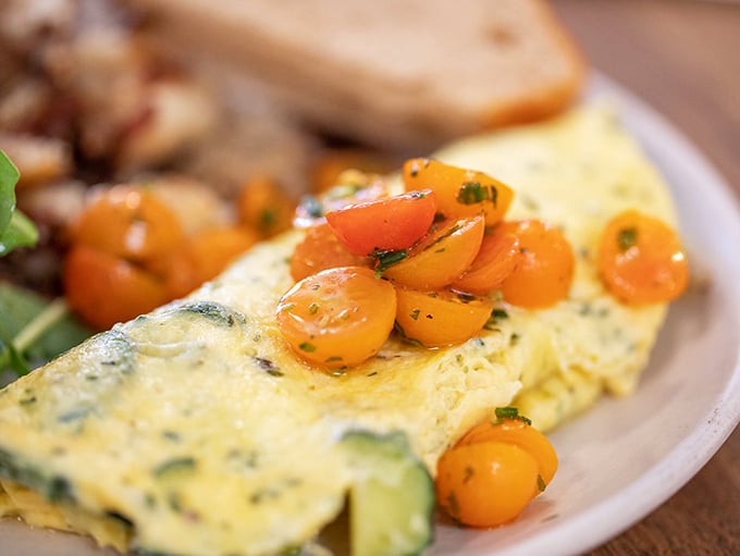The omelet of your dreams doesn't exi— Oh wait, here it is. Fluffy eggs cradle fresh vegetables topped with cherry tomatoes that burst with sunshine in every bite.