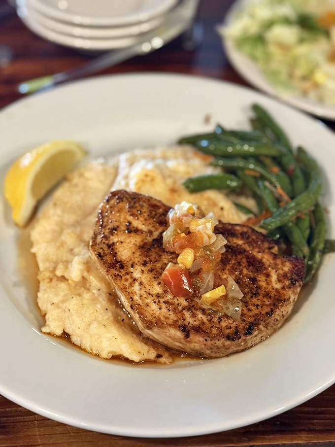 This blackened fish perched atop creamy grits isn't just dinner – it's the Gulf Coast's greatest hits album on a plate.