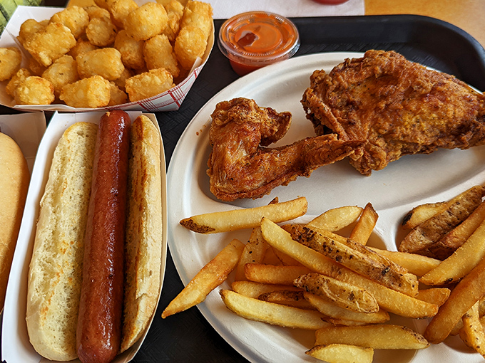 Food harmony achieved: A perfect hot dog, golden tater tots, crispy chicken, and fries sharing a plate like the supergroup of comfort food we all need.