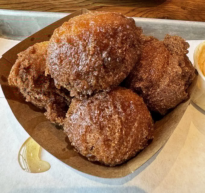 These aren't just hush puppies—they're golden orbs of cornmeal perfection. Crispy exterior, fluffy interior, and enough flavor to make you contemplate ordering seconds before finishing firsts.