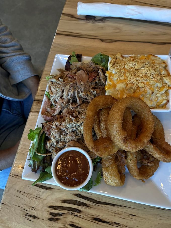 Pulled pork perfection on full display – tender strands of smoky meat alongside golden onion rings and mac & cheese. This plate is Pennsylvania's answer to barbecue bliss.