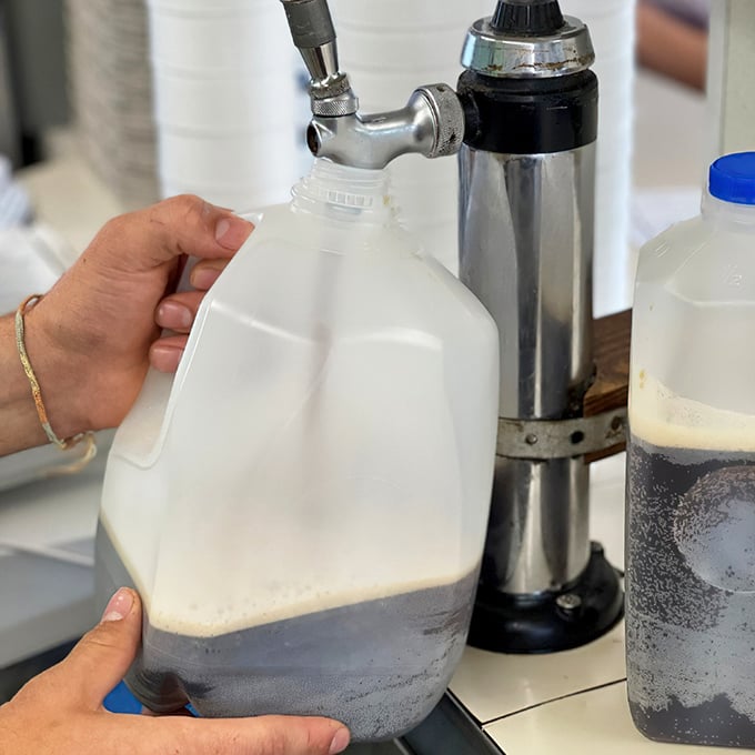 Liquid gold in the making! The homemade root beer gets dispensed into gallon jugs—proof that good things come in simple packages.