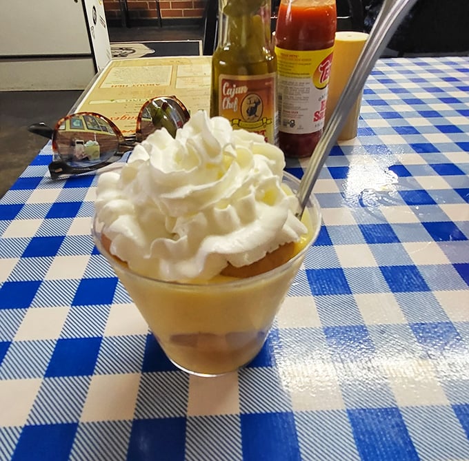 Banana pudding crowned with a cloud of whipped cream—proof that heaven exists and it's served in a glass on checkered tablecloths.