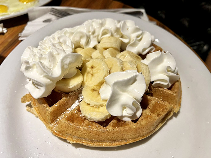 That banana-topped waffle is wearing whipped cream like it's dressed for a party – and you're invited.
