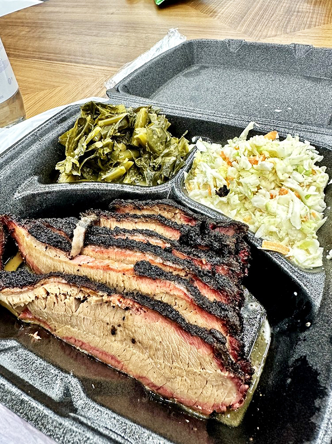 Brisket slices with that perfect pink smoke ring, flanked by collards and coleslaw—the holy trinity of Southern comfort.