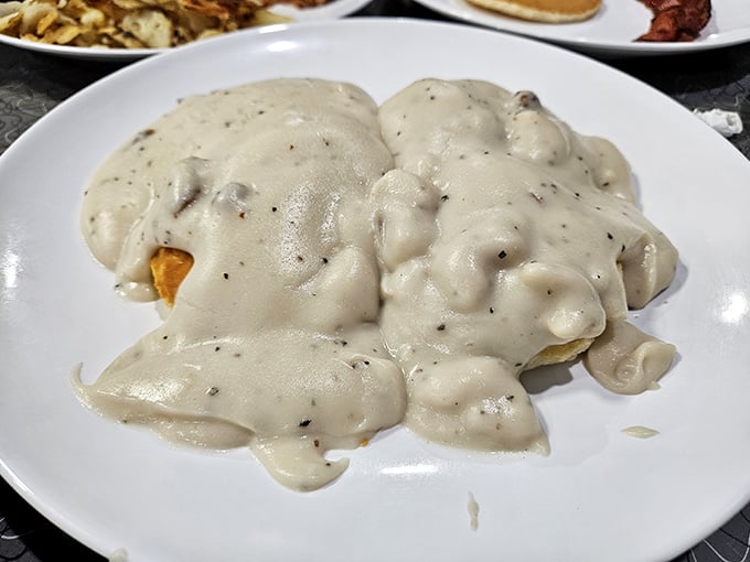 Biscuits and gravy so generous they're practically hidden under a blanket of creamy, peppery goodness—the breakfast equivalent of a warm hug.