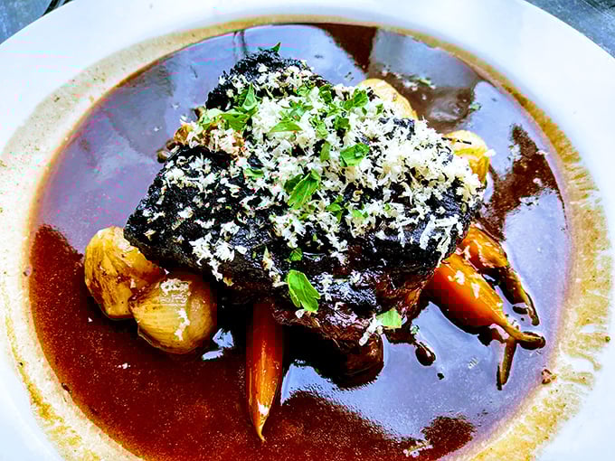 These short ribs aren't just falling off the bone—they're practically jumping onto your fork, swimming in a sauce so rich it probably has its own accountant.