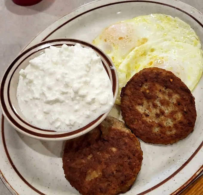 Sausage patties and eggs with a side of cottage cheese—proof that sometimes the simplest breakfast combinations are life's greatest pleasures.