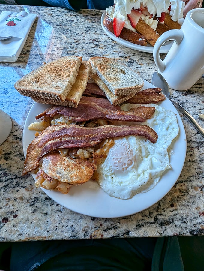 The breakfast trinity—crispy bacon, sunny eggs, and golden toast—arranged with the reverence this holy combination deserves. Coffee cup standing by for moral support.