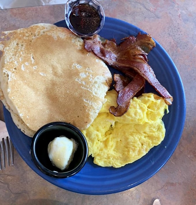 The breakfast trinity: fluffy pancakes, perfectly scrambled eggs, and bacon so crisp it practically shatters when you look at it.