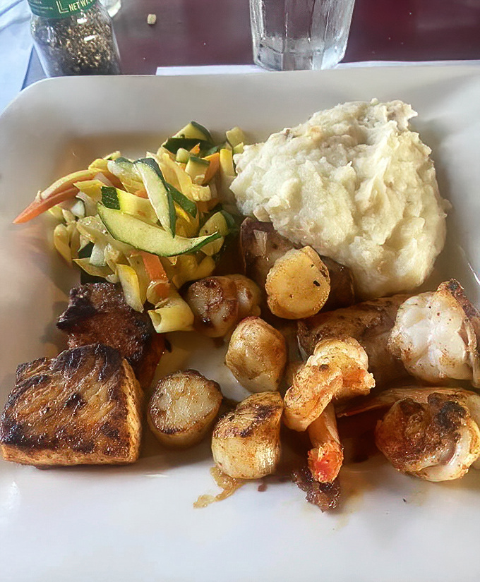 A seafood platter that would make Neptune jealous—perfectly seared fish, plump scallops, and succulent shrimp alongside homestyle sides.