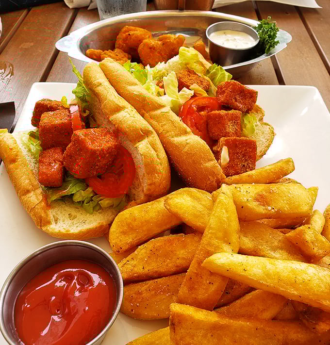 Golden-fried buffalo tofu nestled in a fresh bun with crispy fries—proof that seafood isn't the only star at this tavern.