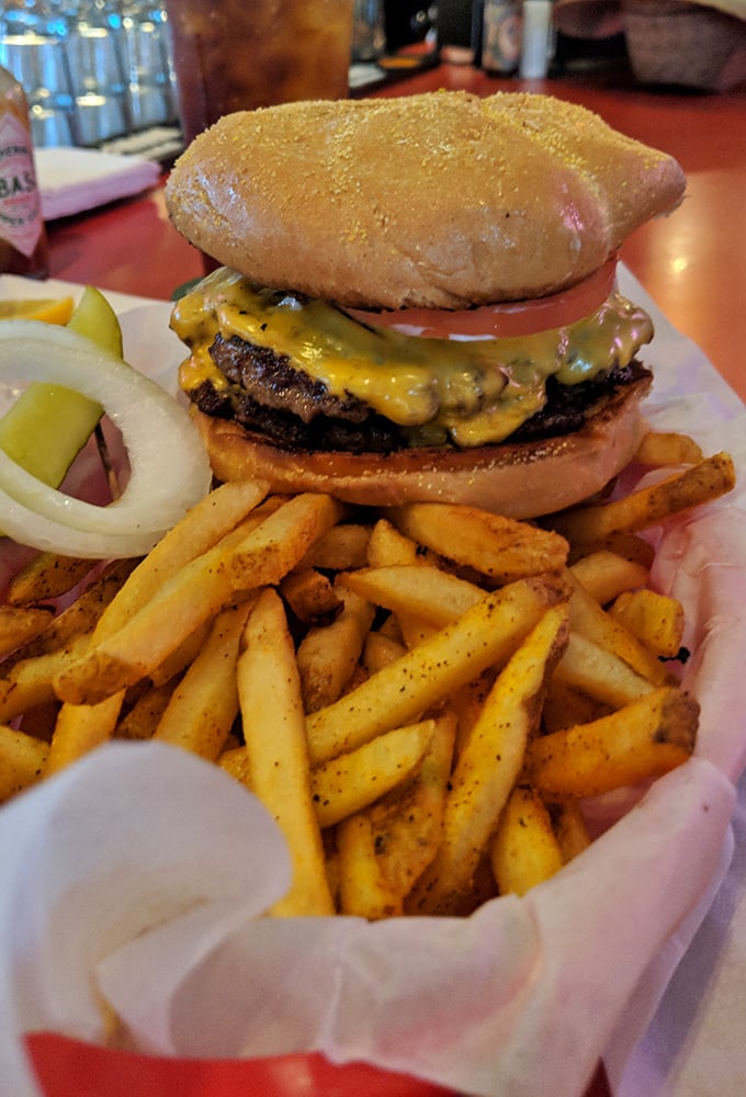 This isn't just a burger; it's edible architecture – a towering masterpiece of beef, cheese, and fresh toppings that demands both hands and your full attention.